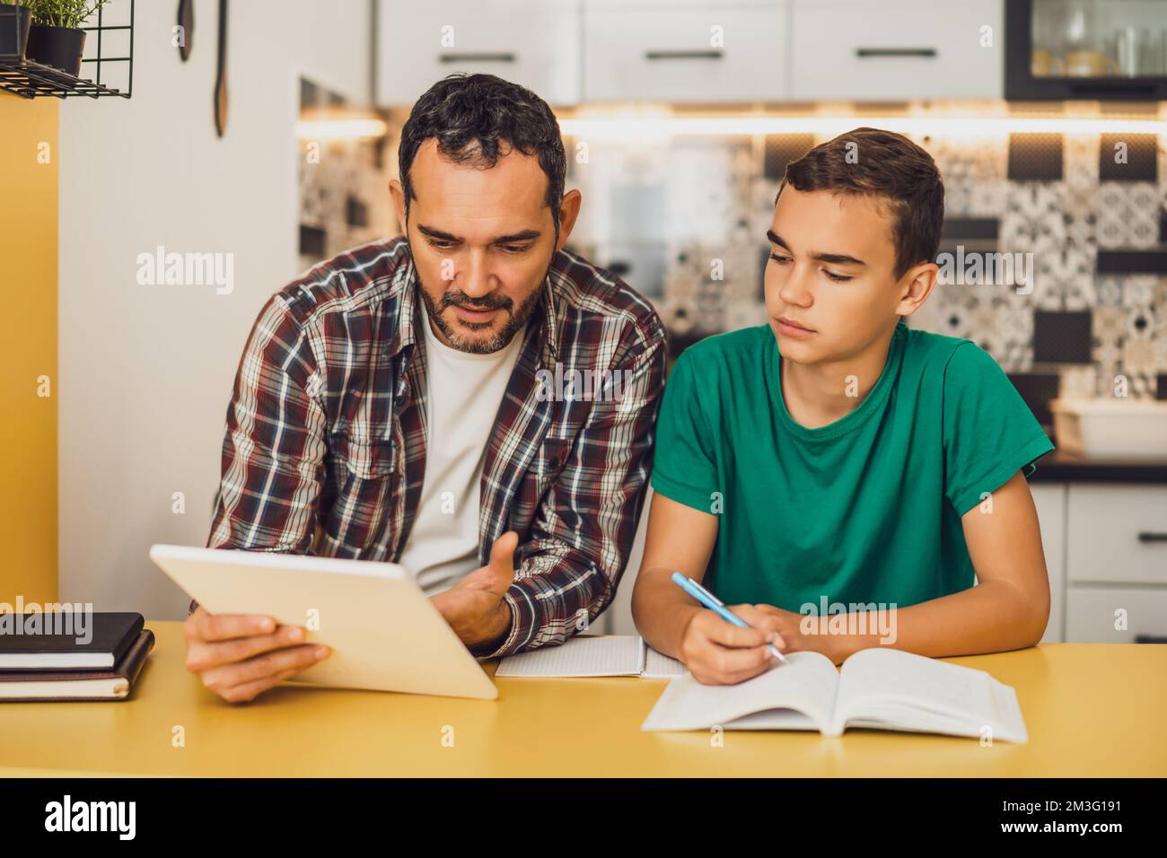 Father is helping his son with learning. They are doing homework ...