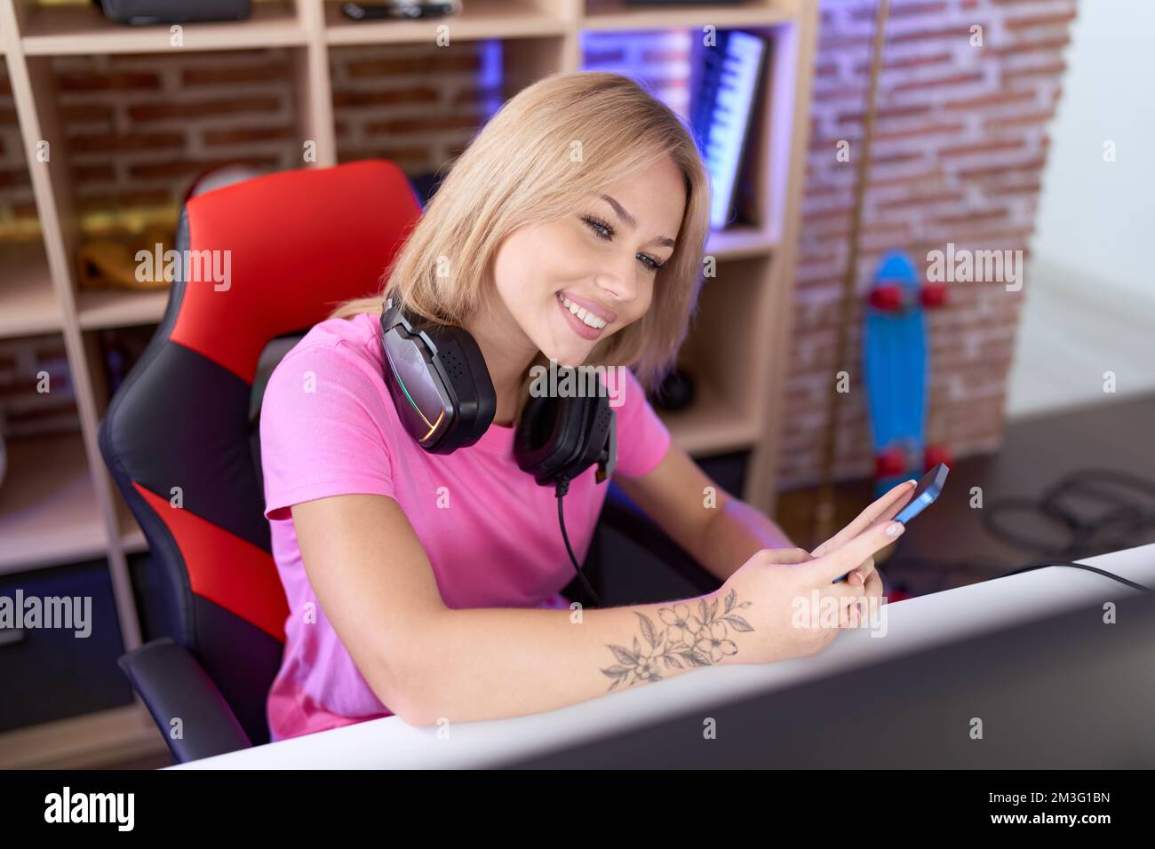 Young blonde woman streamer using computer and smartphone at gaming ...