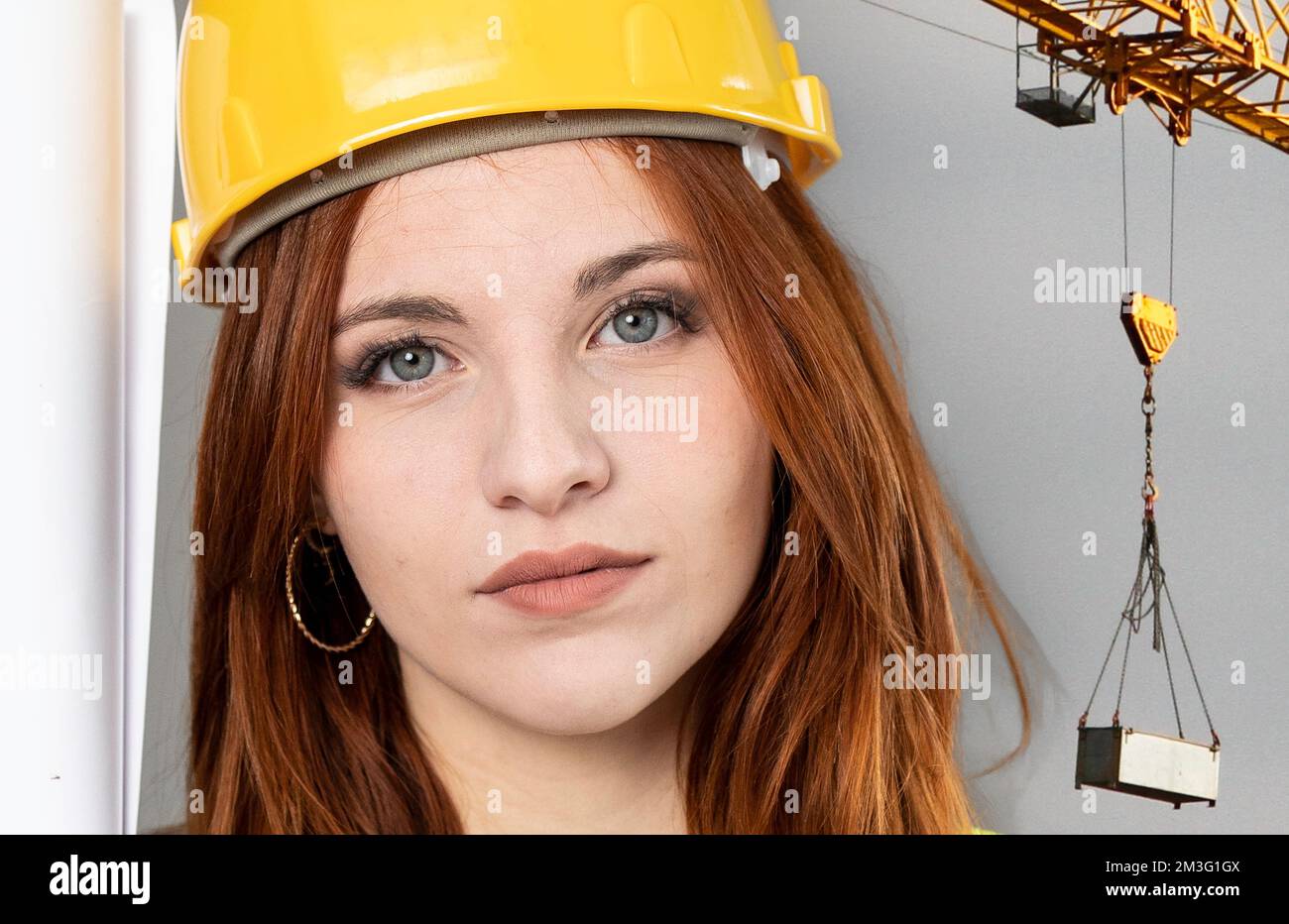 Young female redhead worker of construction site wearing a safety vest and hardhat ...