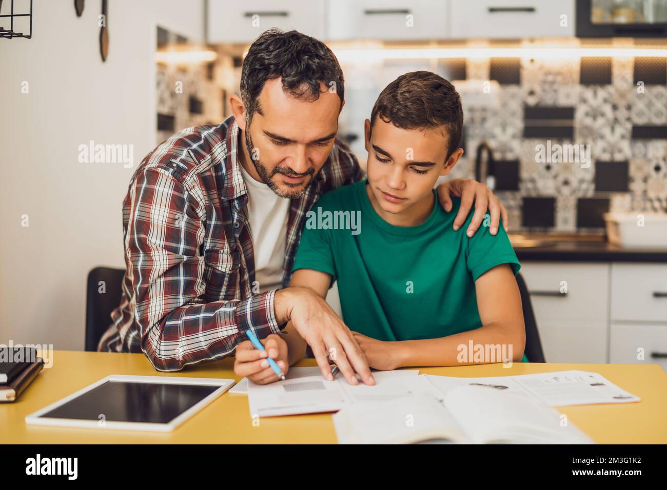 Father is helping his son with learning. They are doing homework ...