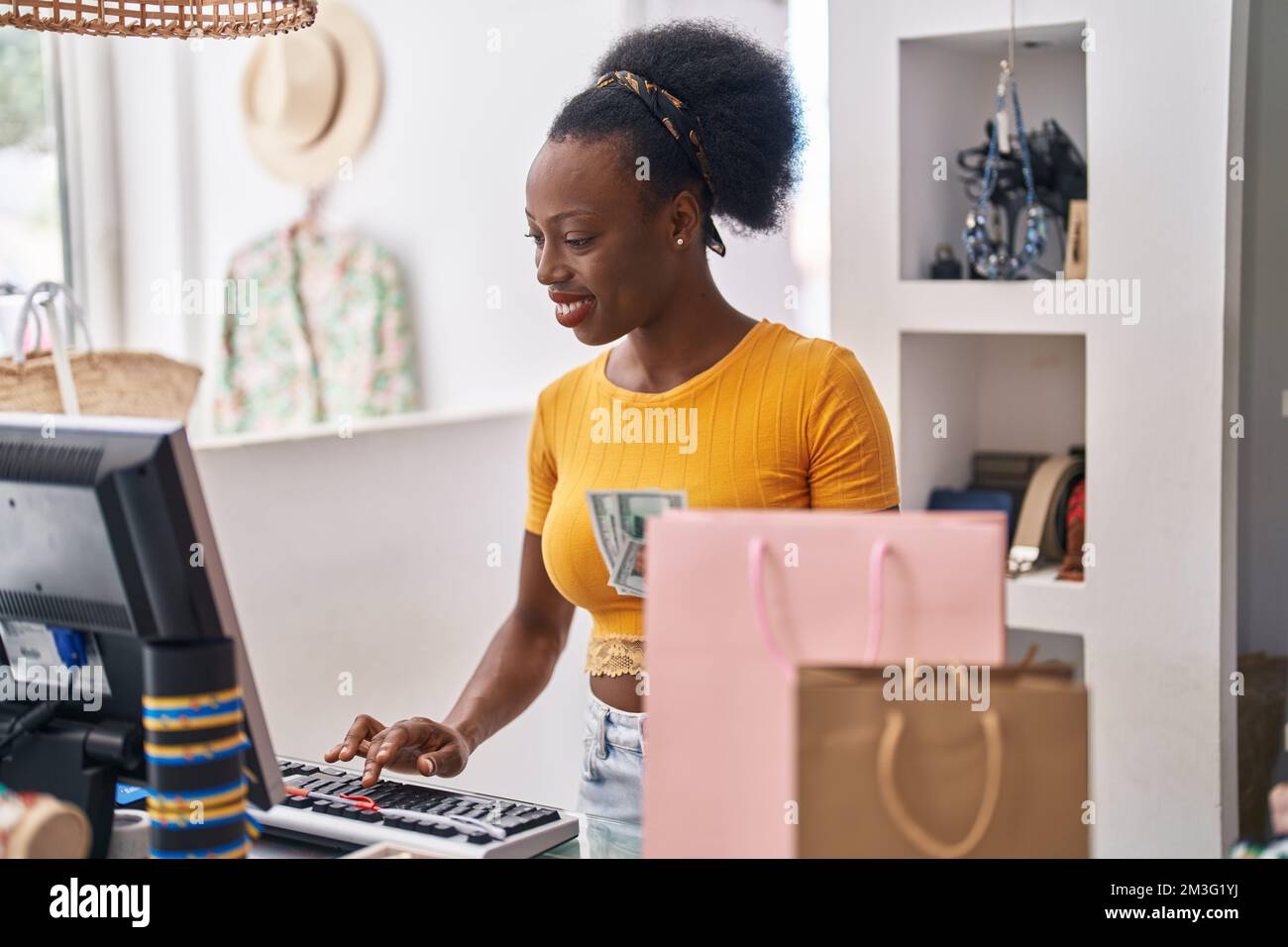 African american woman shop assistant using computer holding dollars at ...