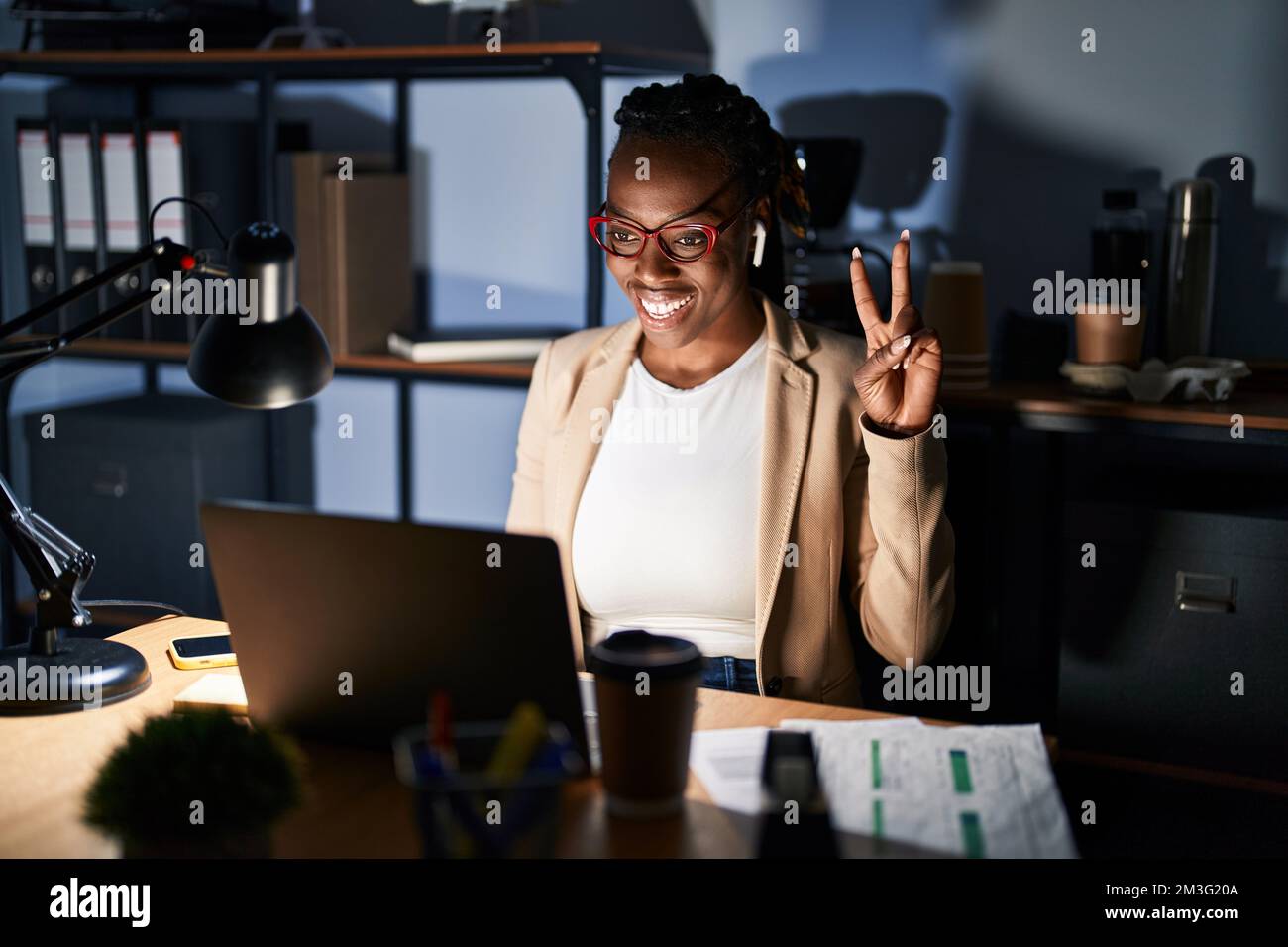 Beautiful black woman working at the office at night showing and ...