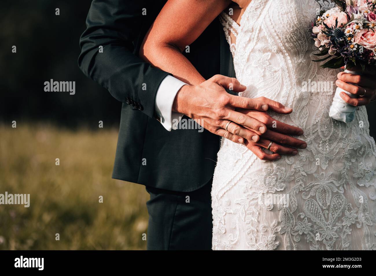 A vertical closeup of a groom hugging bride from back Stock Photo - Alamy