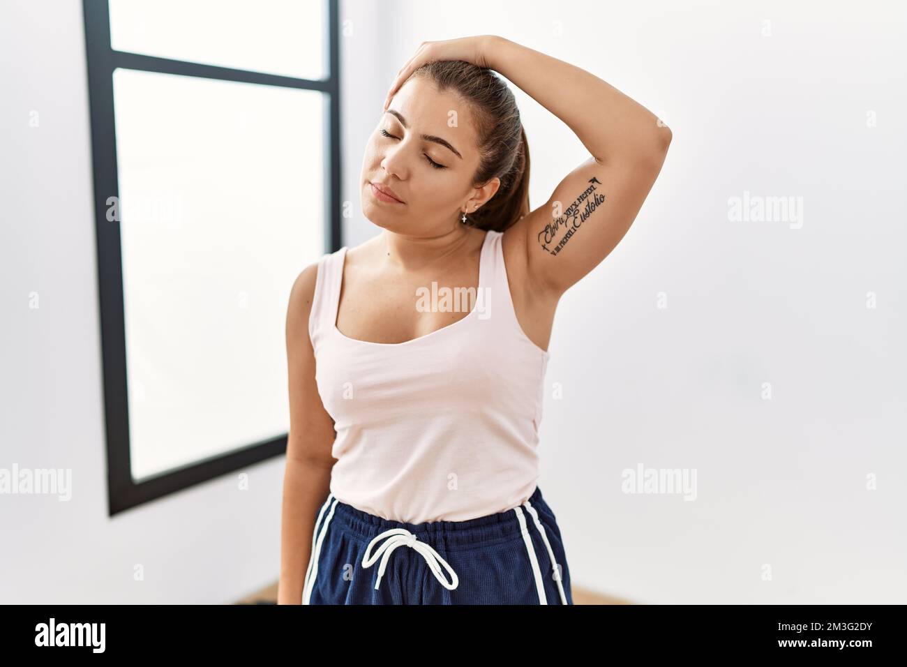 Young hispanic woman stretching at sport center Stock Photo - Alamy