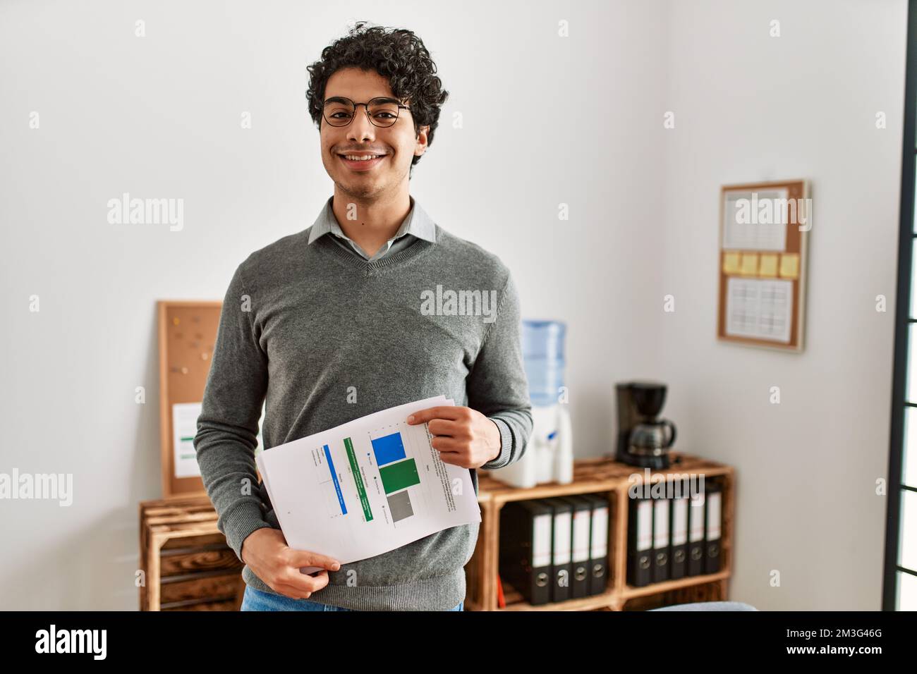 Young hispanic businessman smiling happy holding paperwork at the ...