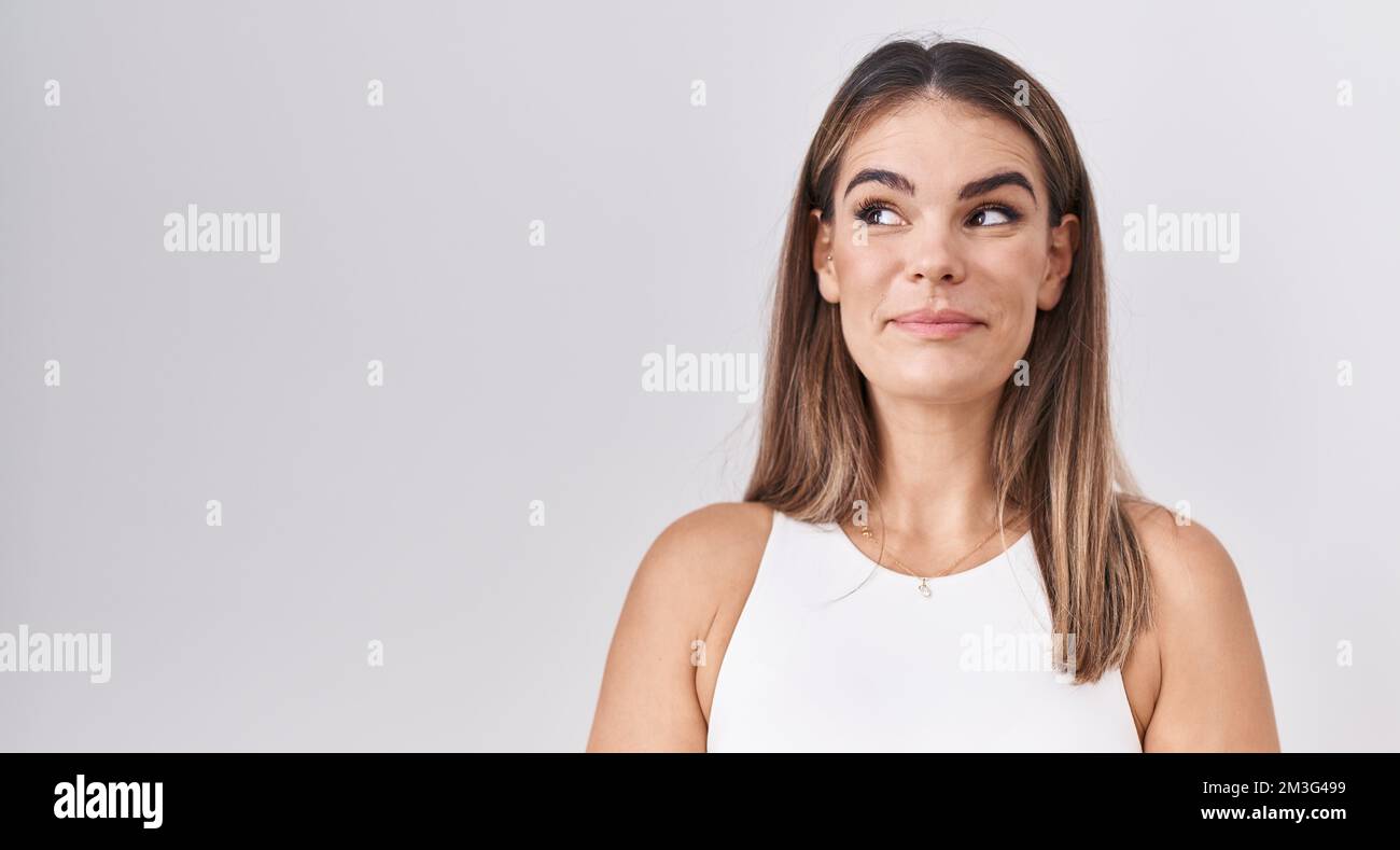 Hispanic young woman standing over white background smiling looking to ...