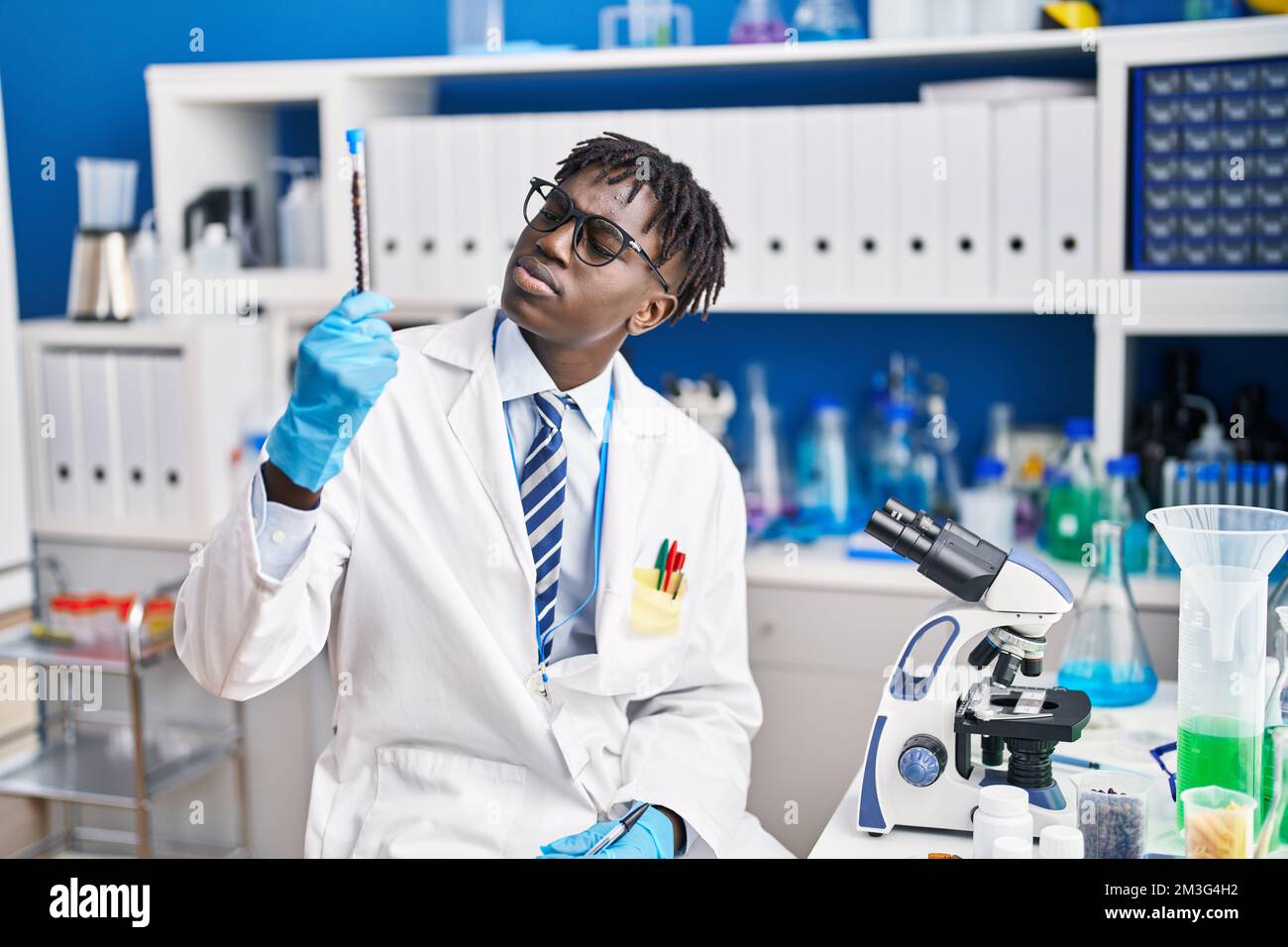 African american man scientist writing report holding test tube at ...