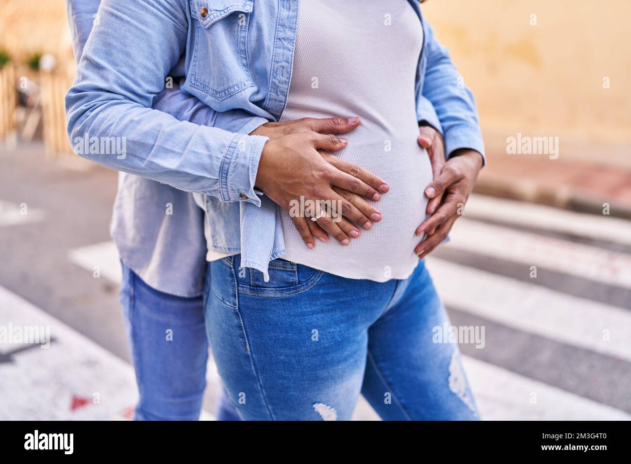Young latin couple expecting baby touching belly hugging each other at street Stock Photo - Alamy