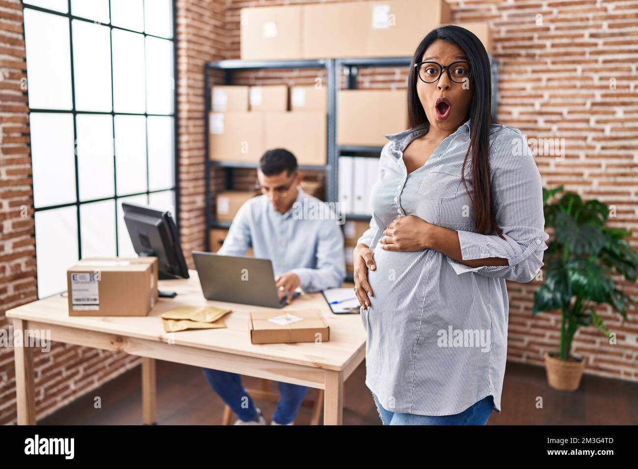 Young hispanic woman expecting a baby working at small business ...