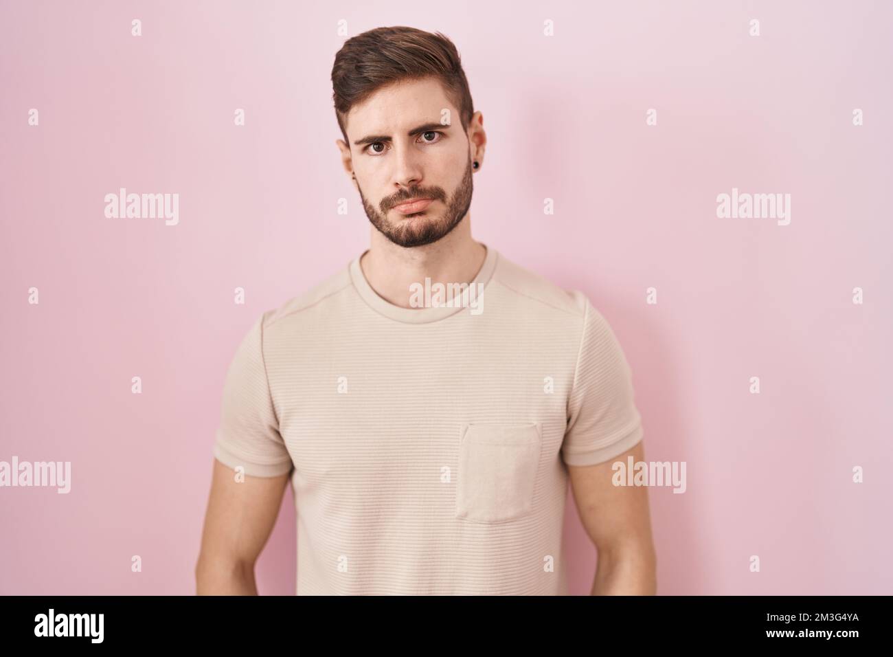 Hispanic man with beard standing over pink background depressed and ...