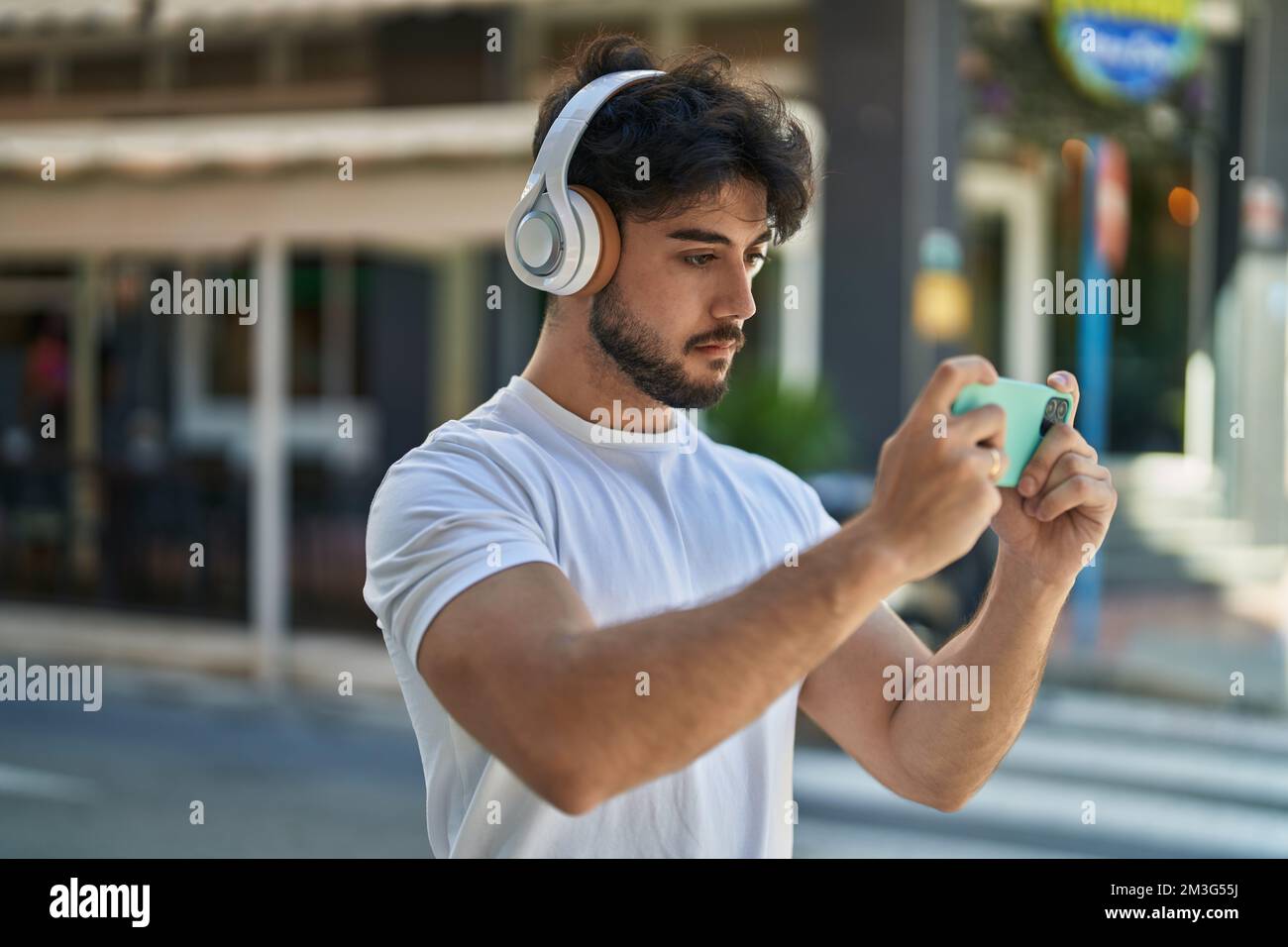 Young hispanic man playing video game at street Stock Photo - Alamy