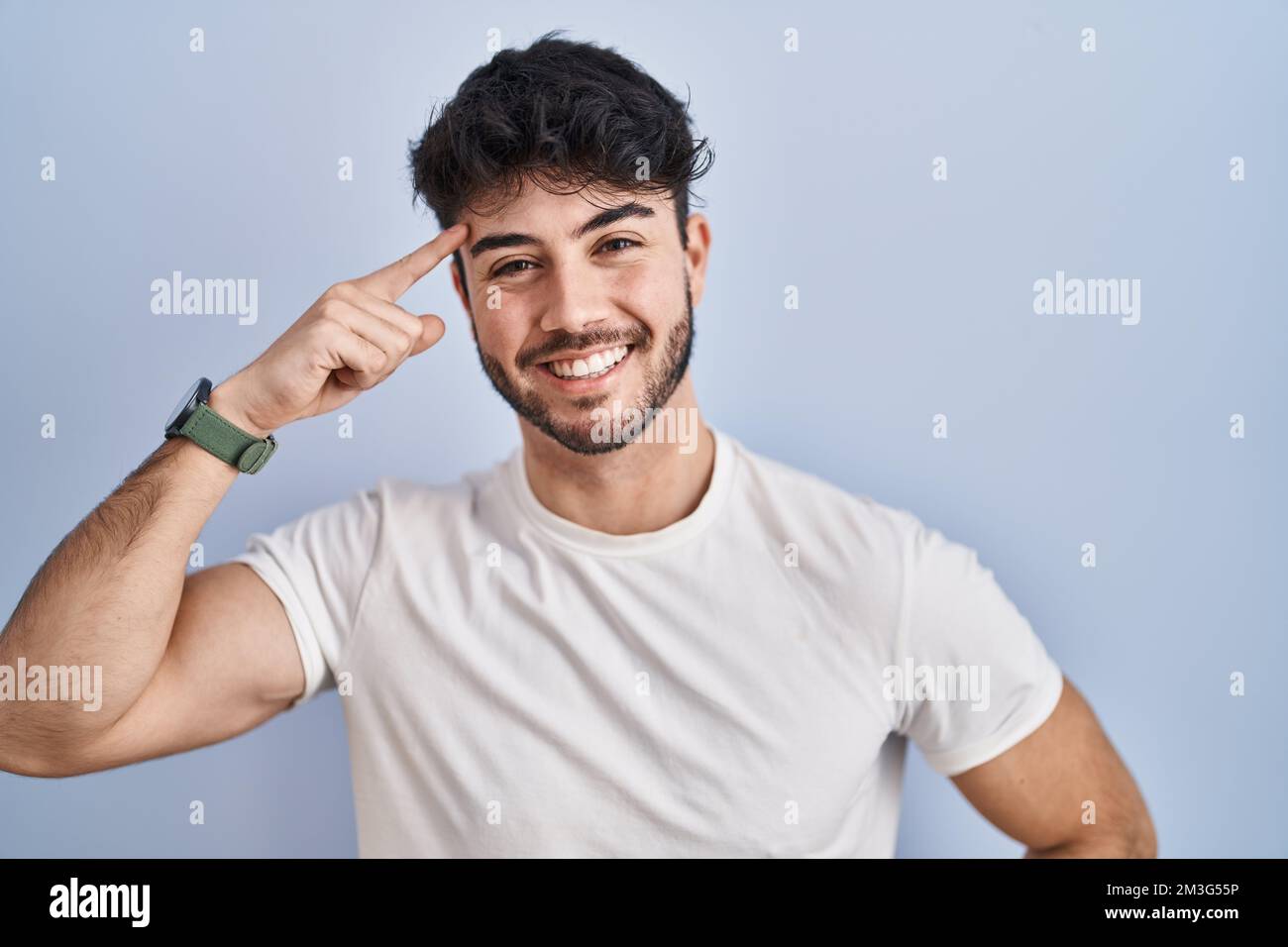 Hispanic man with beard standing over white background smiling pointing ...
