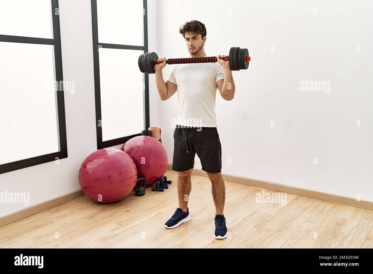 Young hispanic man training with dumbbell at sport center Stock Photo ...
