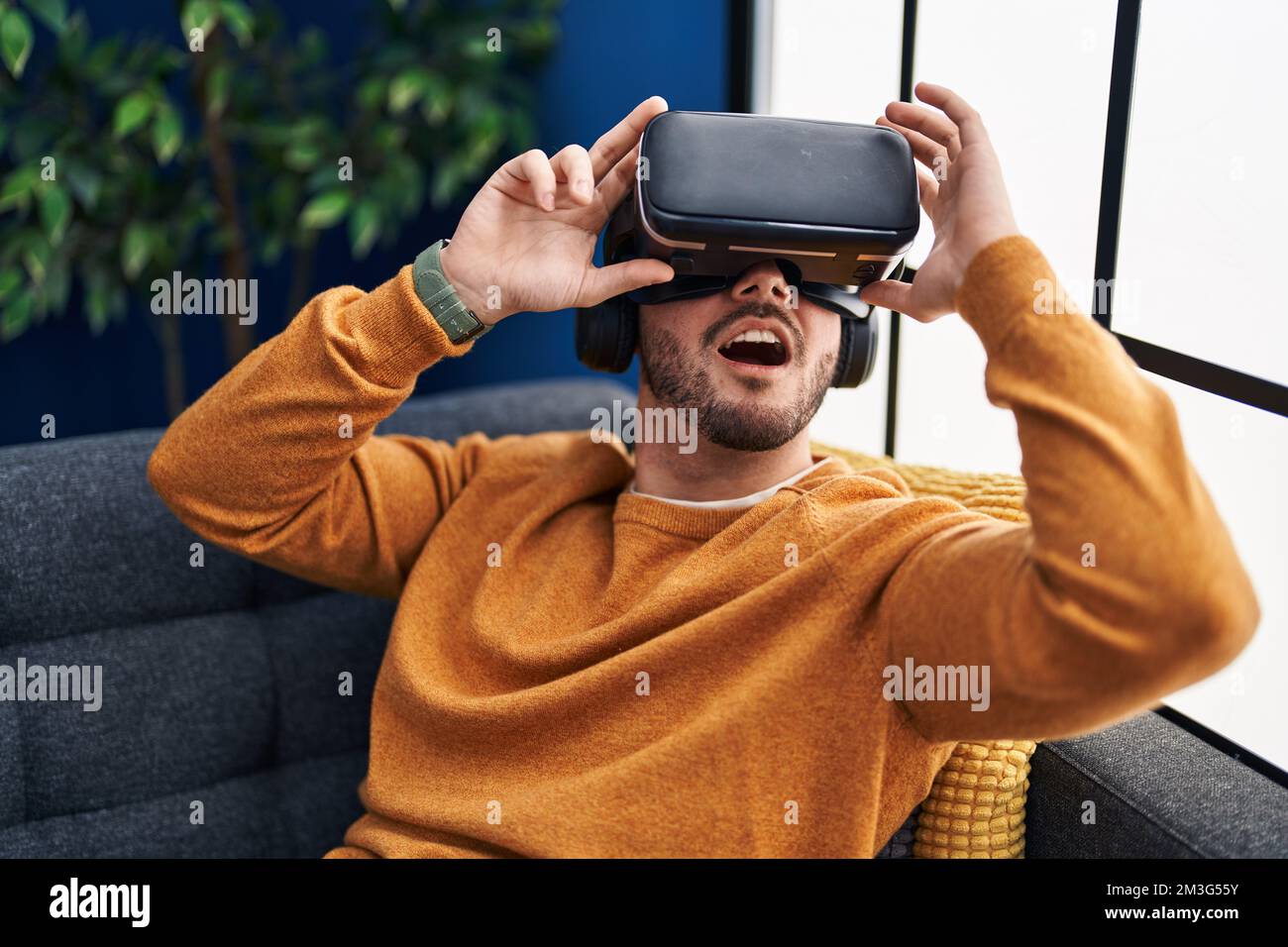 Young hispanic man playing video game using virtual reality glasses at ...