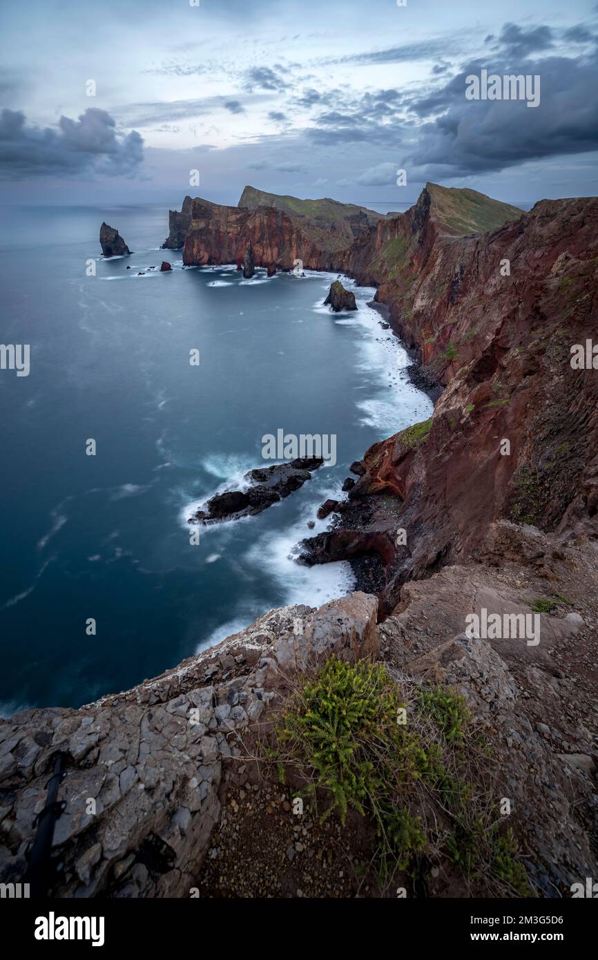 Red cliffs and rocks in the sea, coastal landscape, at sunset ...
