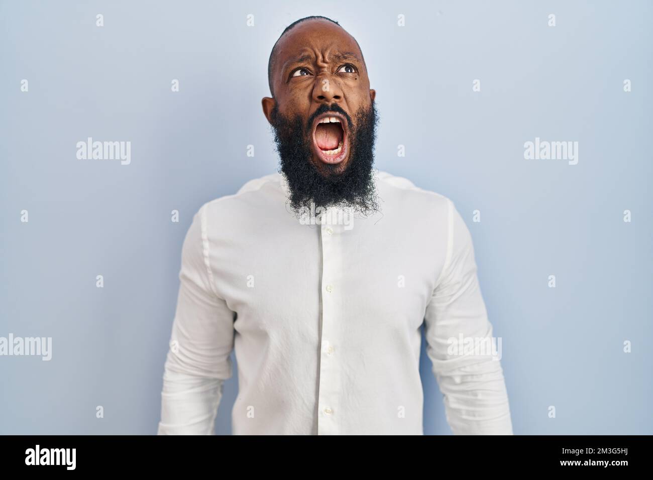 African american man standing over blue background angry and mad ...