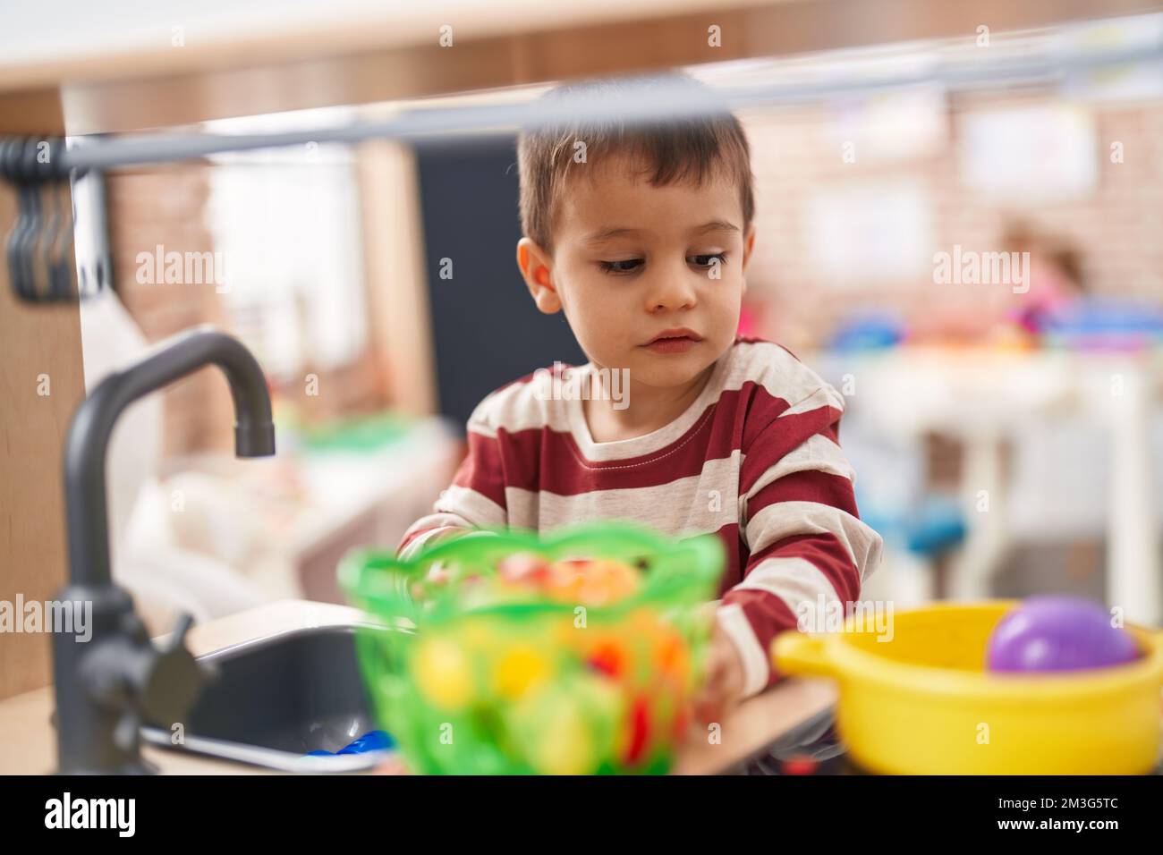 Adorable toddler playing with play kitchen standing at kindergarten ...