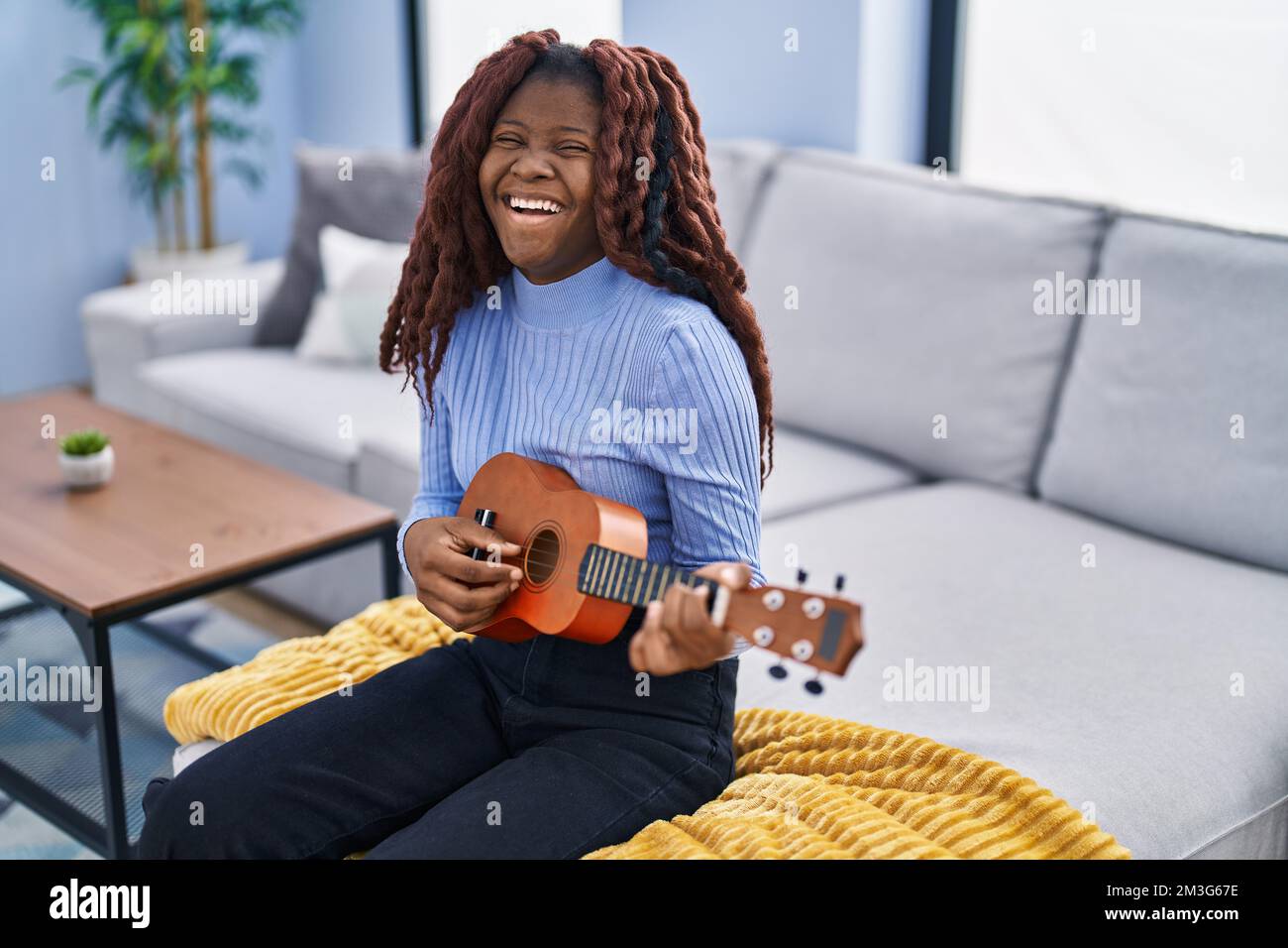 African american woman playing ukulele sitting on sofa at home Stock ...