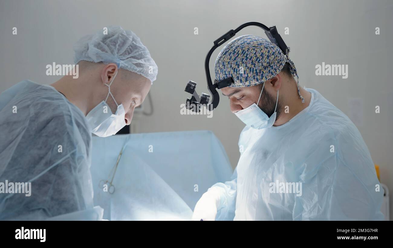 Medical team of surgeons in operating theater performing operation on a ...