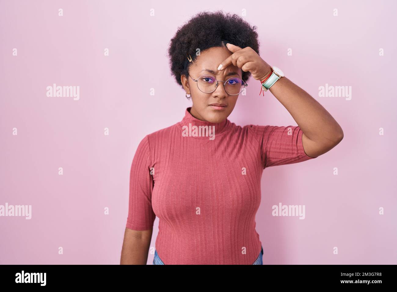 Beautiful african woman with curly hair standing over pink background ...