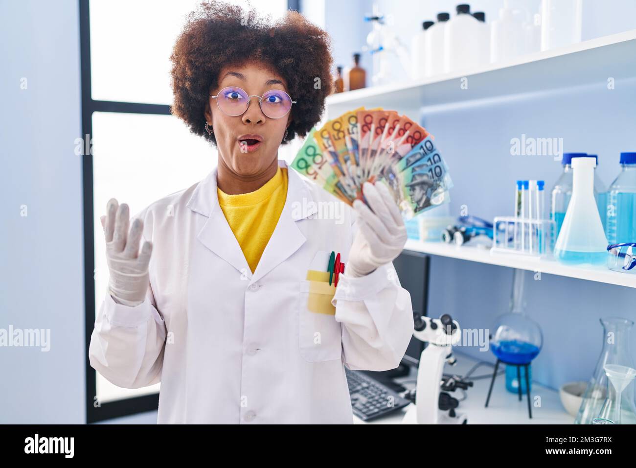 Young african american woman working at scientist laboratory holding ...
