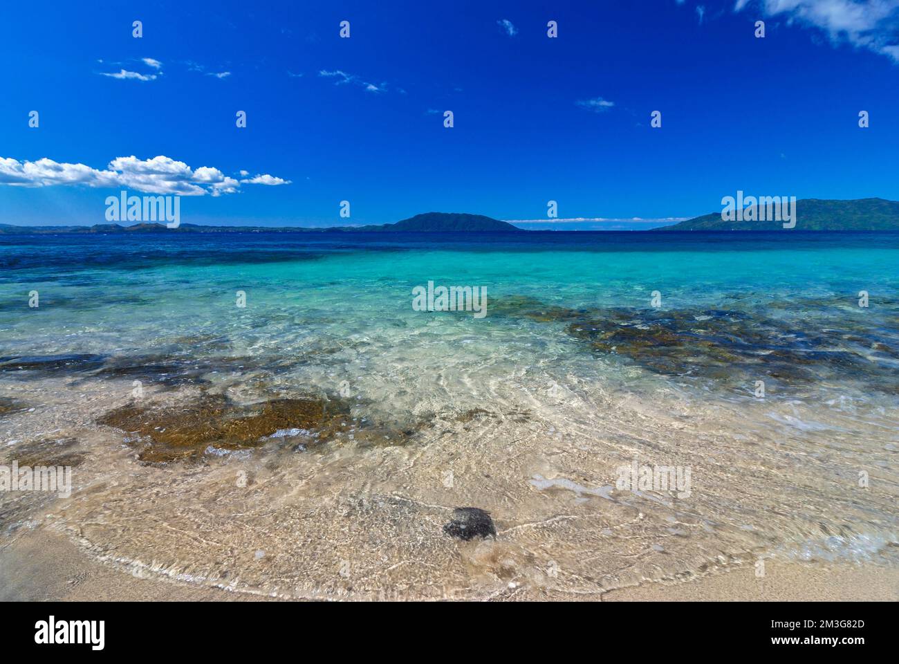 Crystal clear water and white sand beach, in the background Nosy Be ...