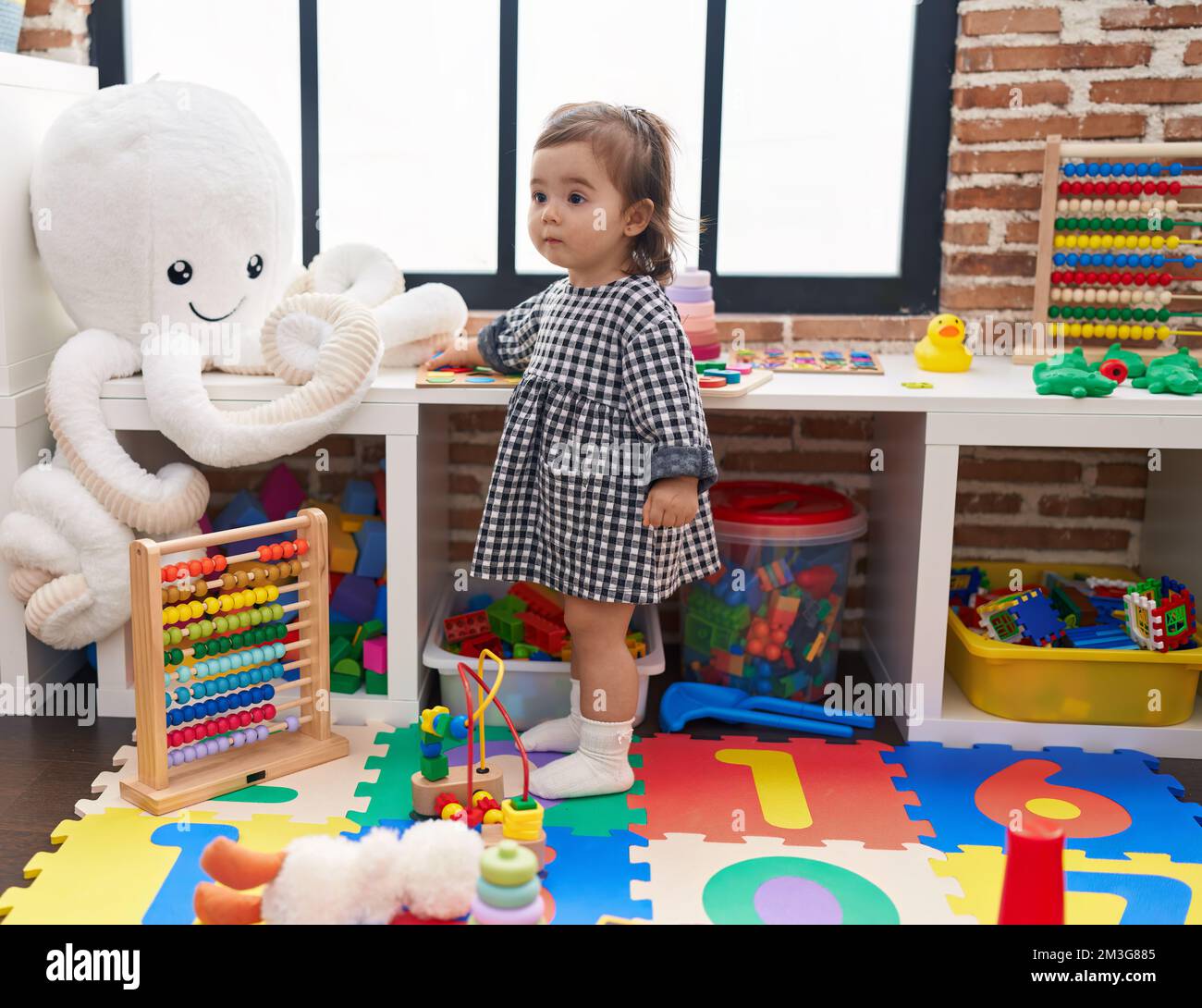 Adorable chinese girl standing with relaxed expression at kindergarten ...