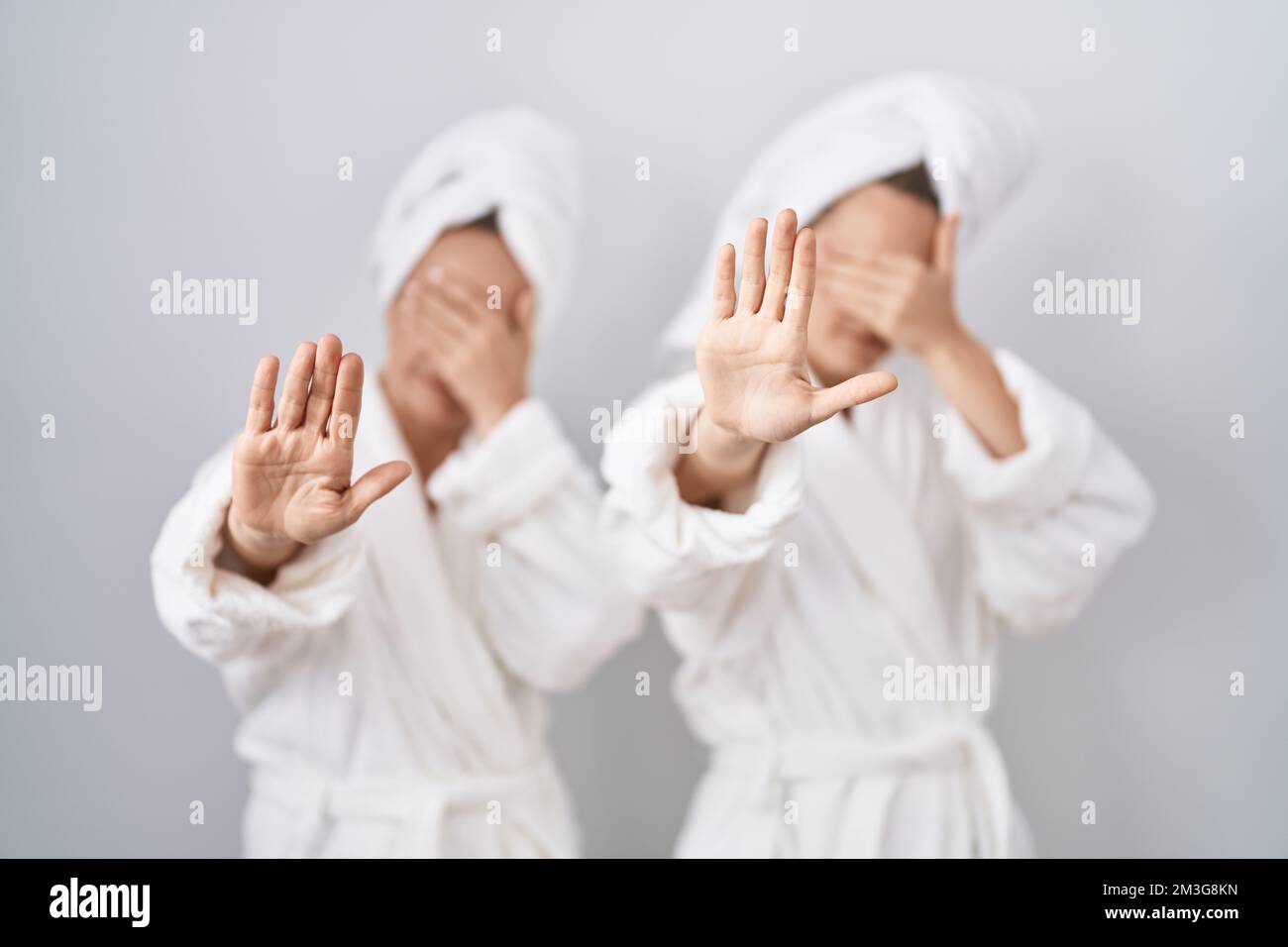 Middle age woman and daughter wearing white bathrobe and towel covering ...