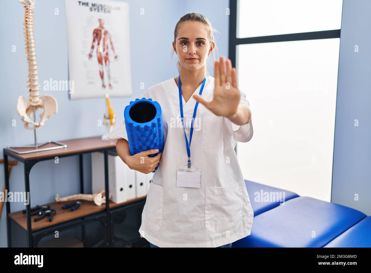 Young physiotherapist woman holding foam roll at the clinic with open ...
