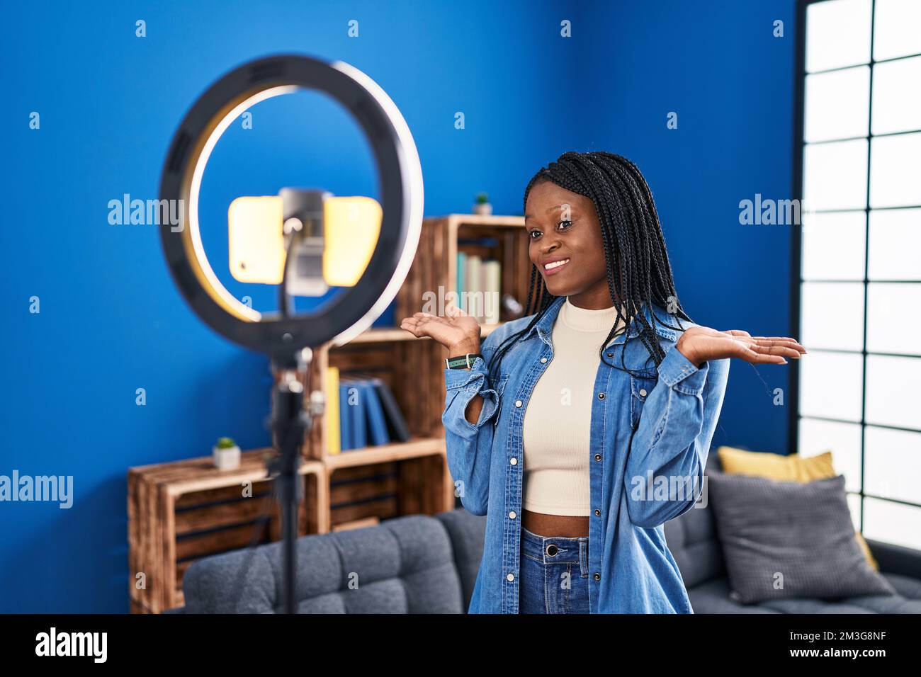 African woman with braids recording vlog tutorial with smartphone at ...