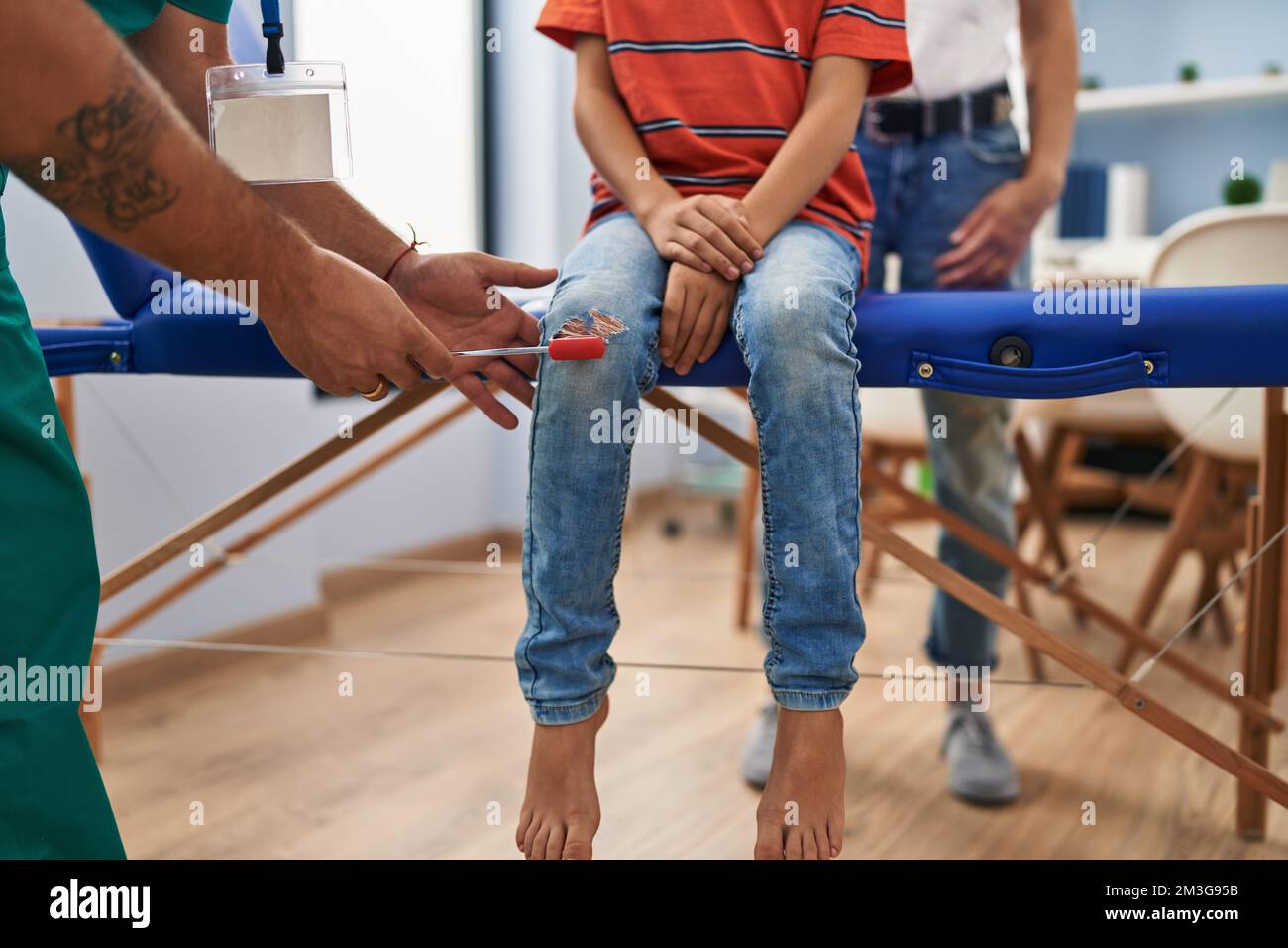 Family having medical consultation doing reflex knee test at clinic ...