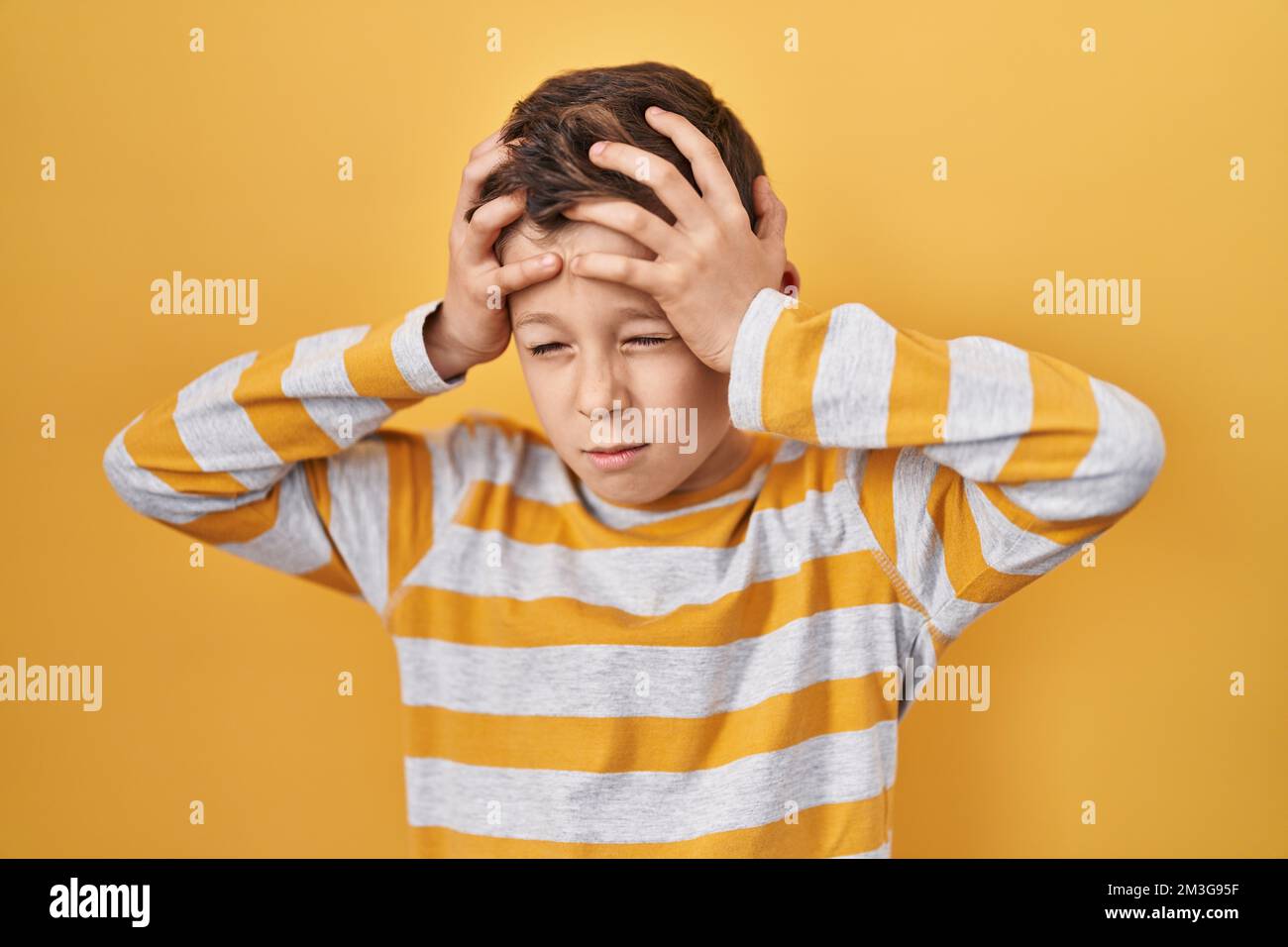 Young caucasian kid standing over yellow background suffering from ...