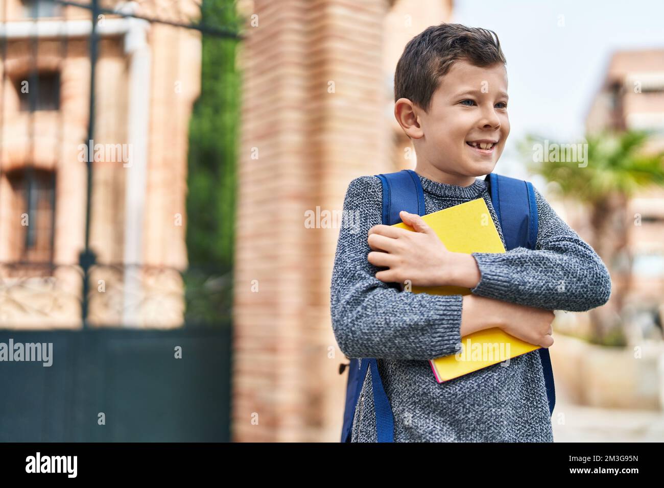 Blond child student hugging book standing at street Stock Photo - Alamy