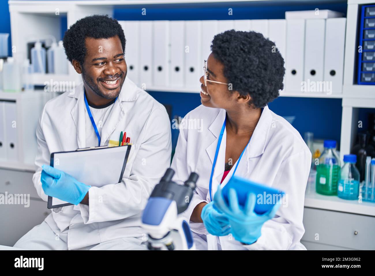 African american man and woman scientists using touchpad write on document at laboratory Stock ...