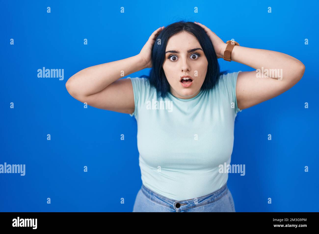 Young modern girl with blue hair standing over blue background crazy ...
