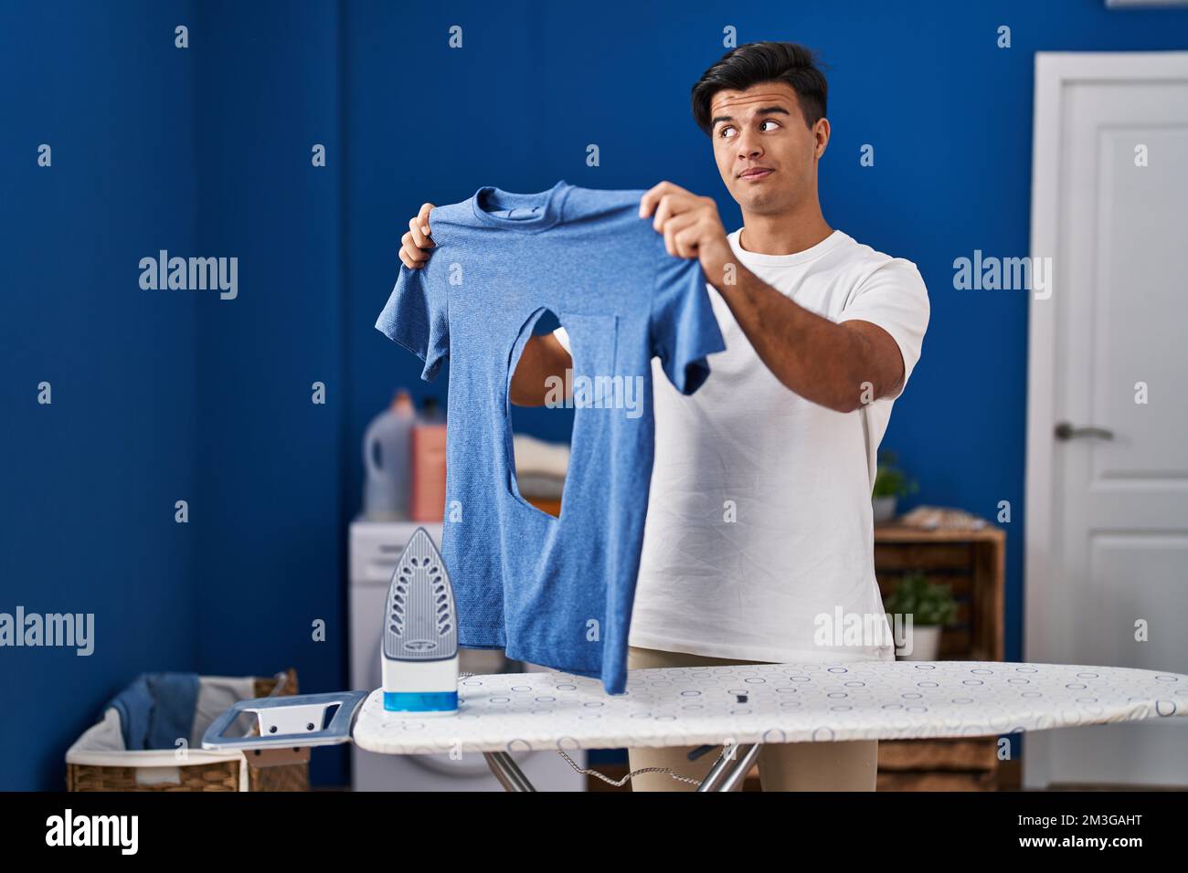 Hispanic man ironing holding burned iron shirt at laundry room smiling ...