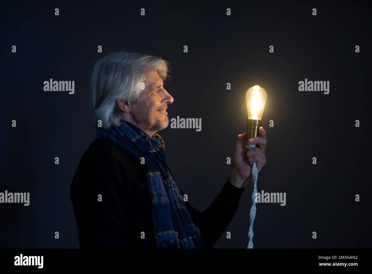 Older gentleman with scarf and shining light bulb smiles Stock Photo ...