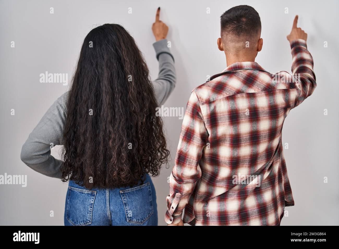 Young hispanic couple standing over white background posing backwards ...