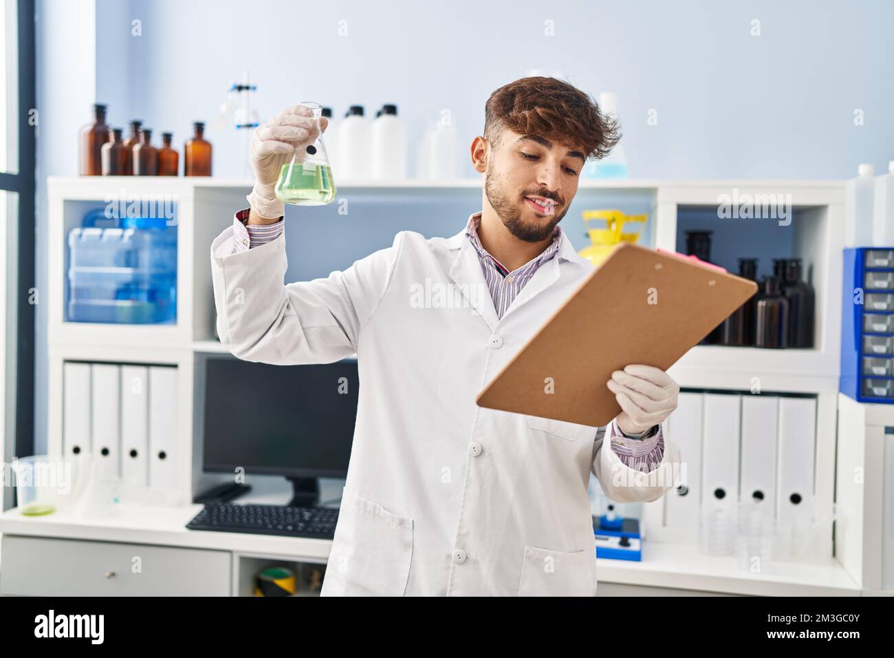 Young arab man scientist measuring liquid reading report at laboratory Stock Photo - Alamy