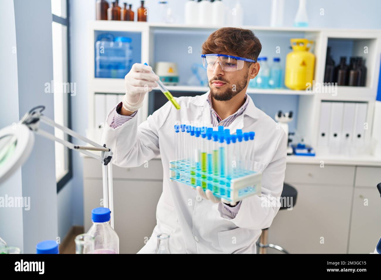 Young arab man scientist measuring liquid holding test tubes at ...