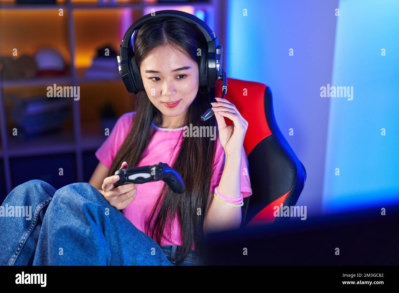Young chinese woman streamer playing video game using joystick at ...