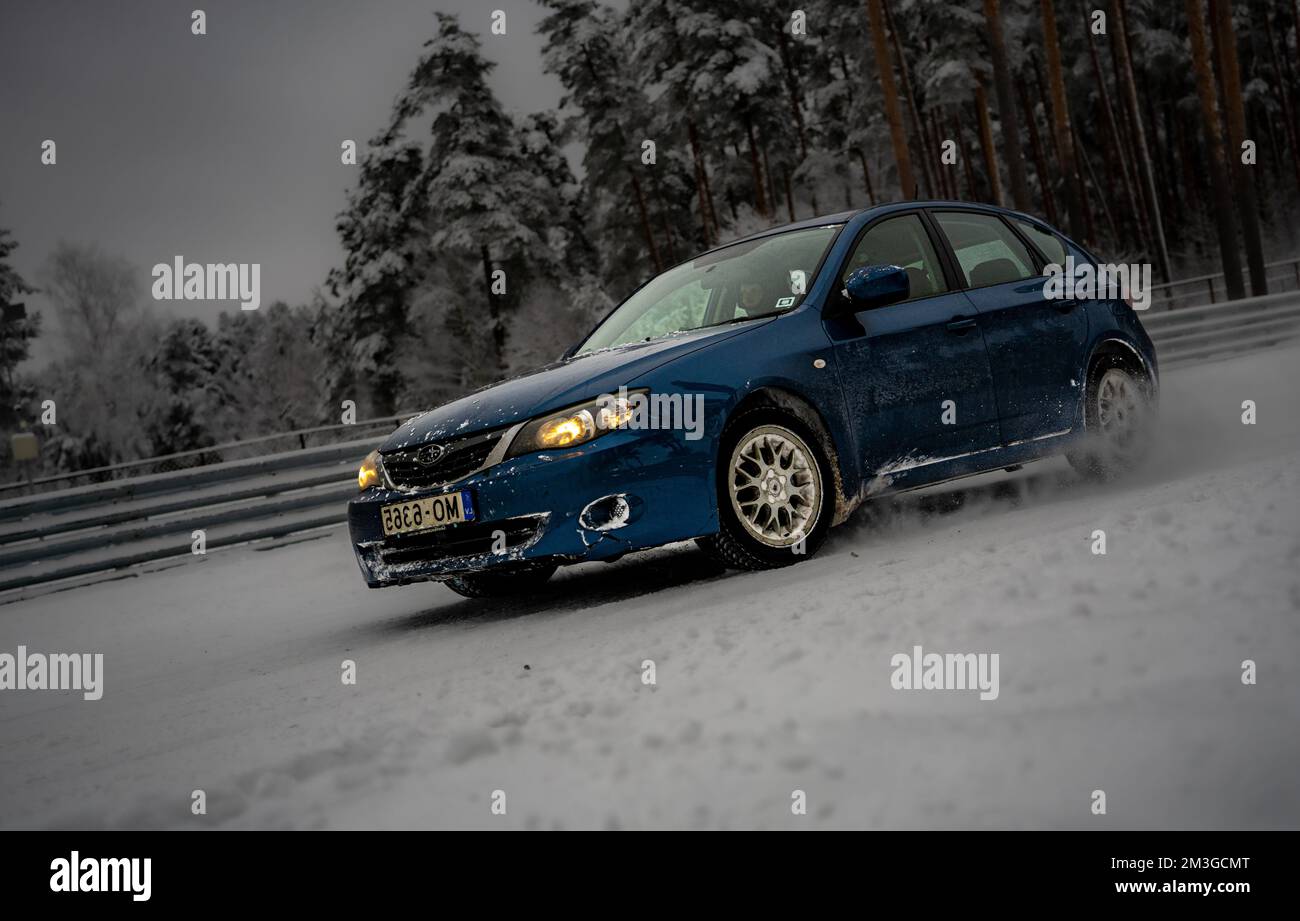12-12-2022 Riga, Latvia a blue car driving down a snowy road next to a ...