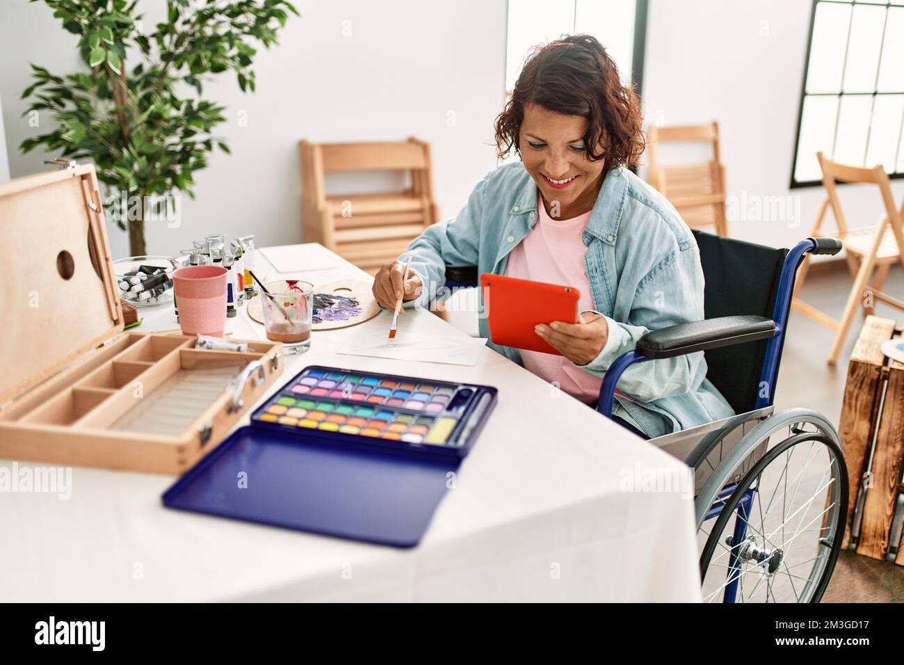 Middle age hispanic disabled artist woman drawing using touchpad ...