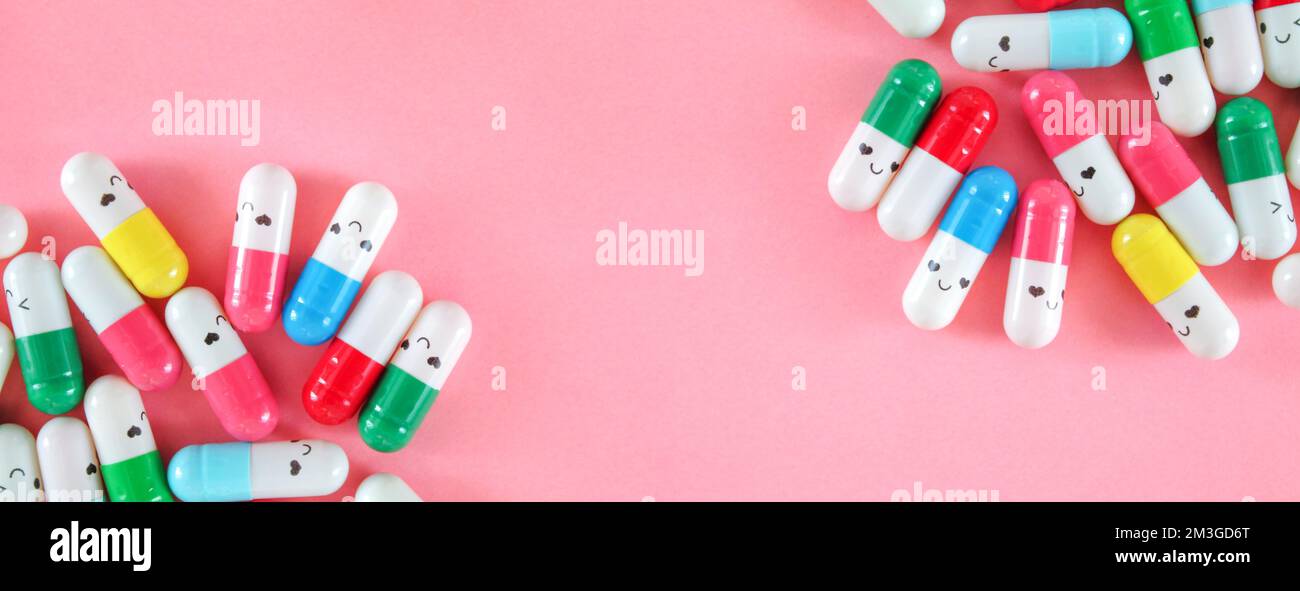 Colorful medical pills with funny faces on light pink background top ...