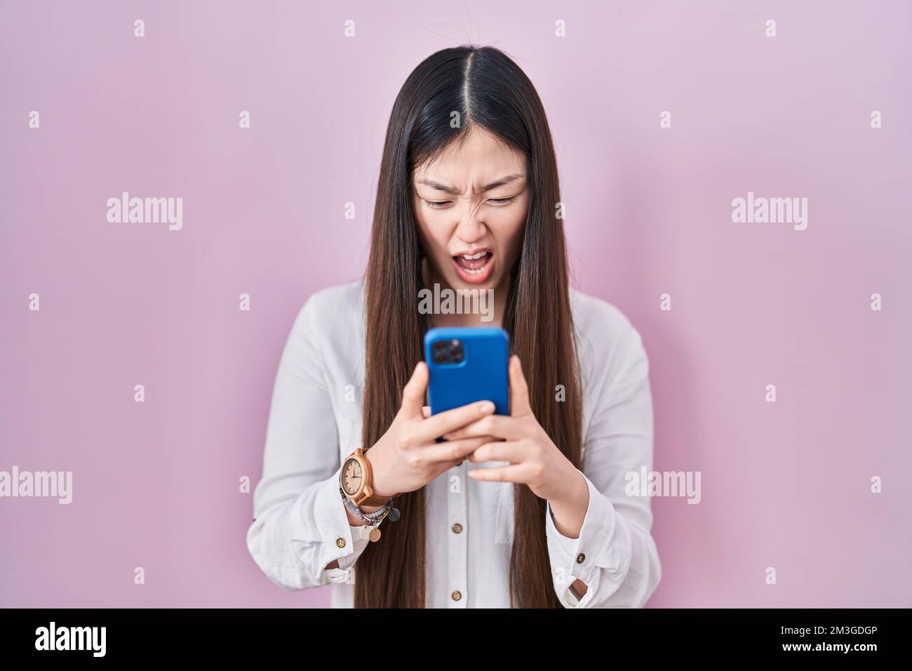 Chinese young woman using smartphone typing message angry and mad ...