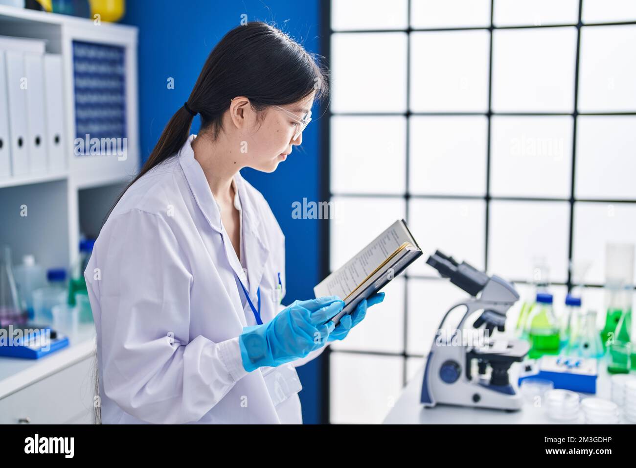 Chinese woman scientist reading book at laboratory Stock Photo - Alamy