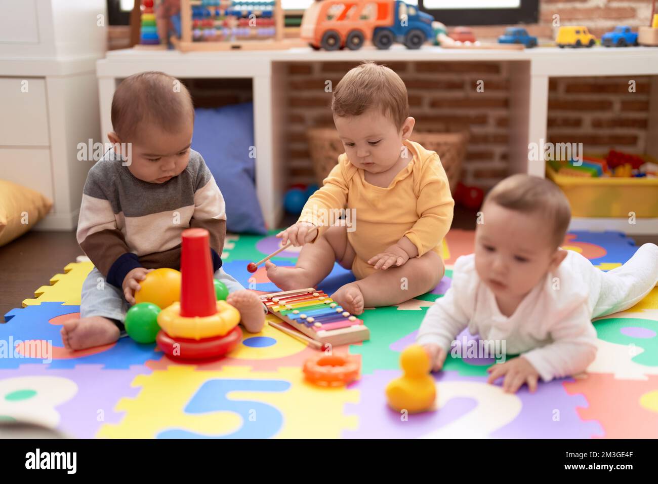 Group of toddlers playing with toys sitting on floor at kindergarten ...