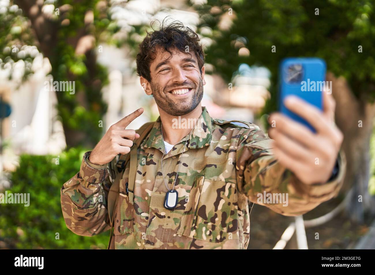 Hispanic young man wearing camouflage army uniform doing video call ...