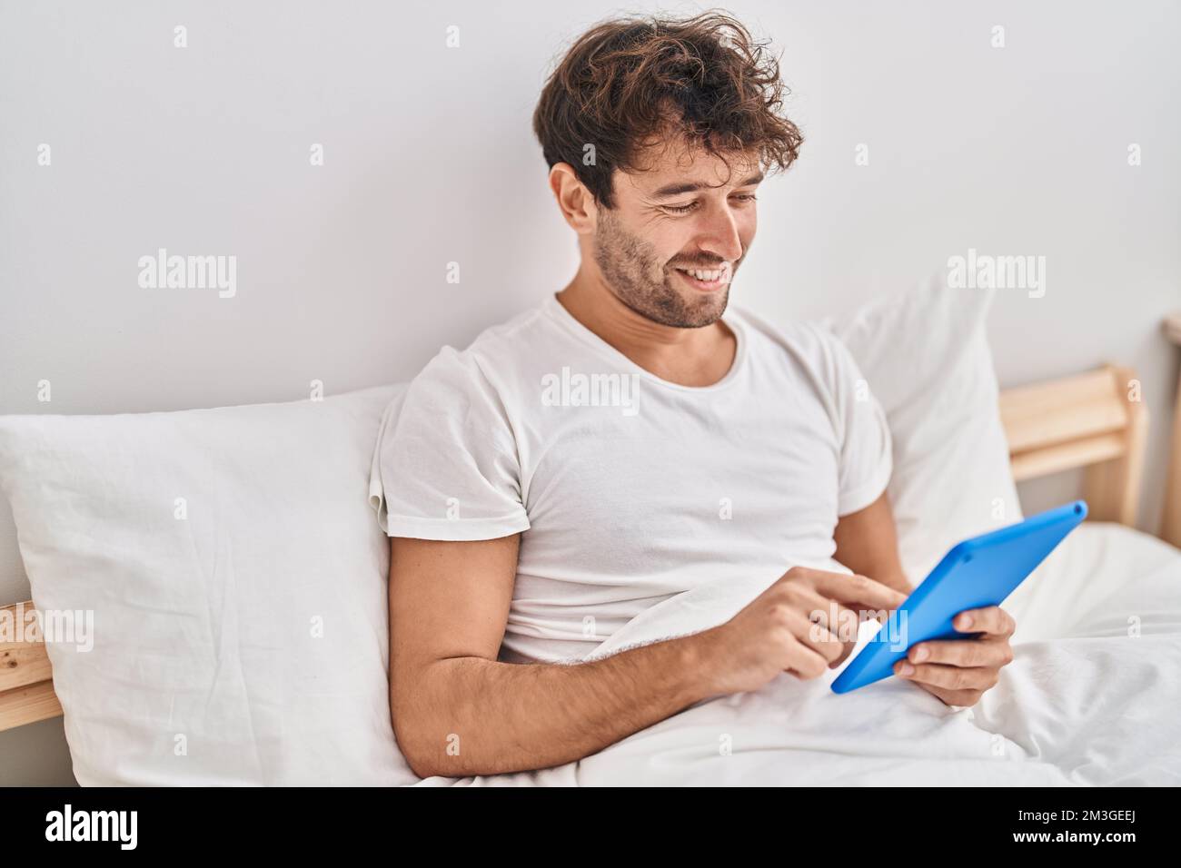 Young man using touchpad sitting on bed at bedroom Stock Photo - Alamy