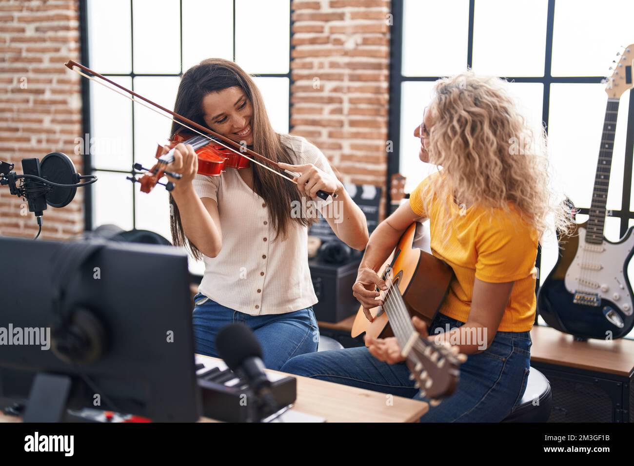 Two women musicians playing violin and classical guitar at music studio ...